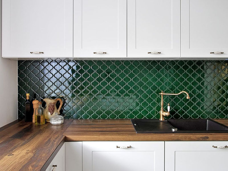 Zelená mozaika ve tvaru arabesky za kuchyňskou linkou
